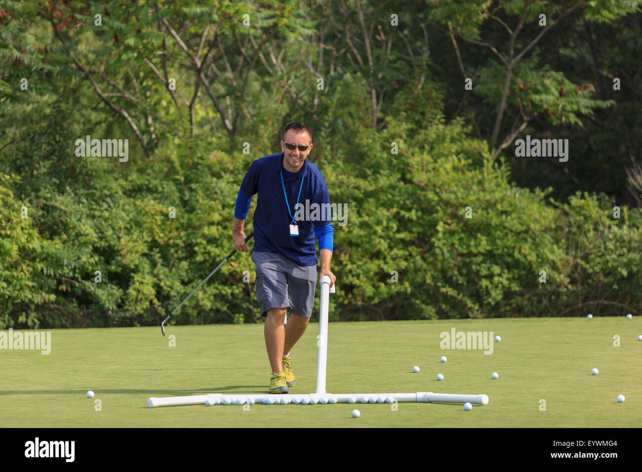 Assistant at a golf course gathering balls for play Stock Photo - Alamy