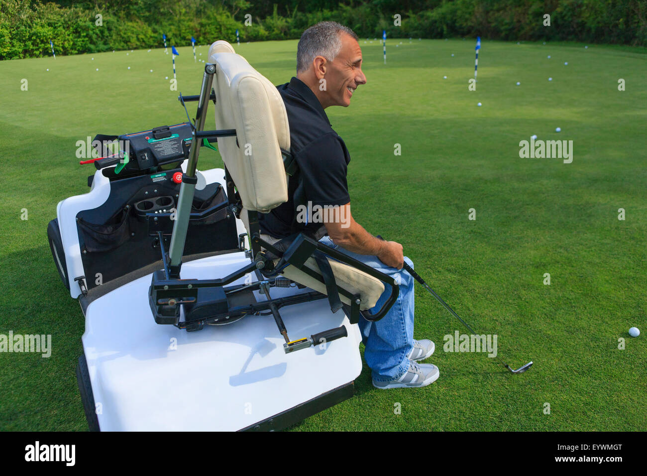 Man with a spinal cord injury in an adaptive cart at golf putting green ...