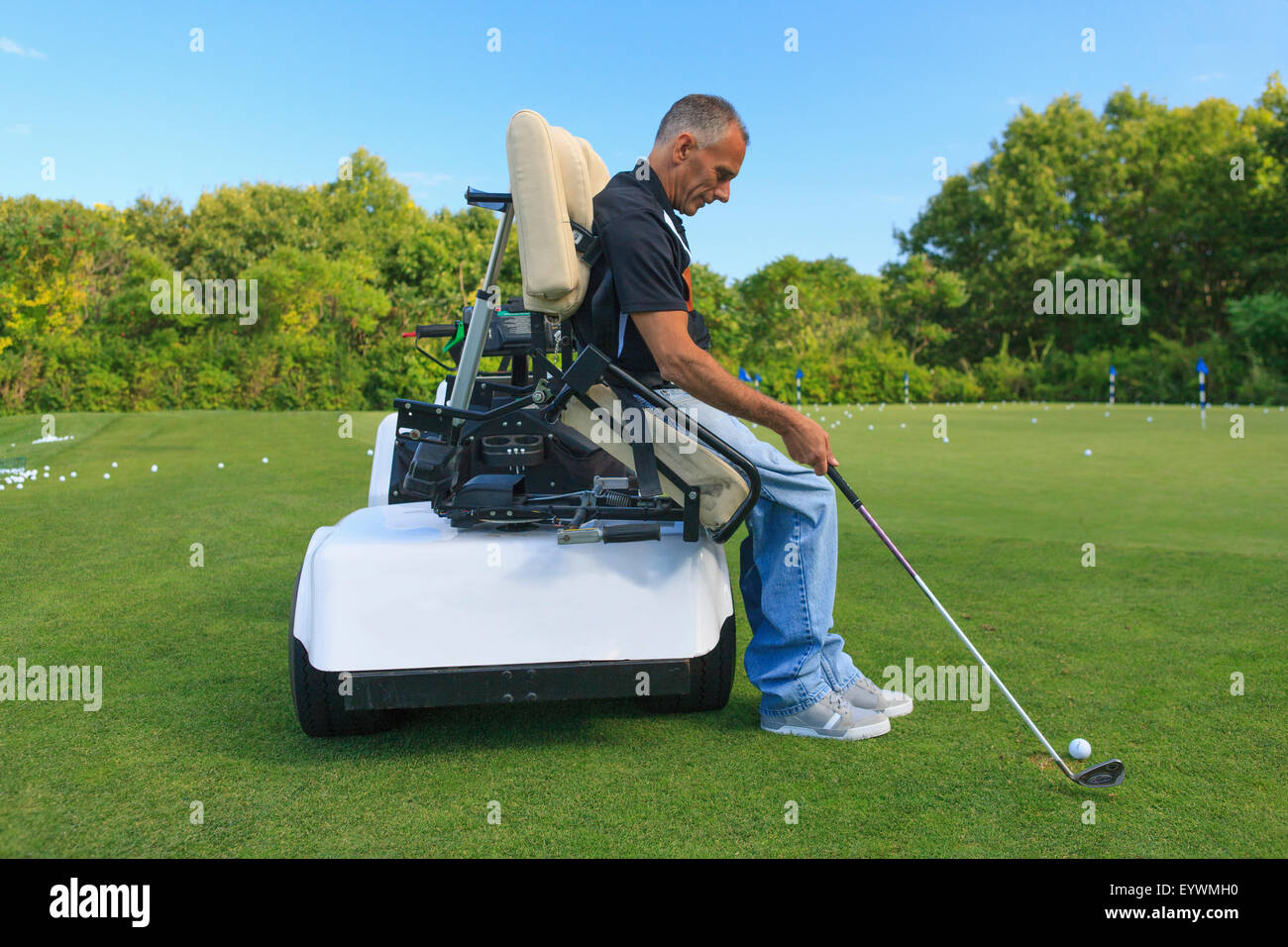Man with a spinal cord injury in an adaptive cart at golf putting green ...