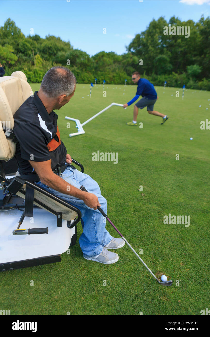 Man with a spinal cord injury in an adaptive cart at golf putting green ...