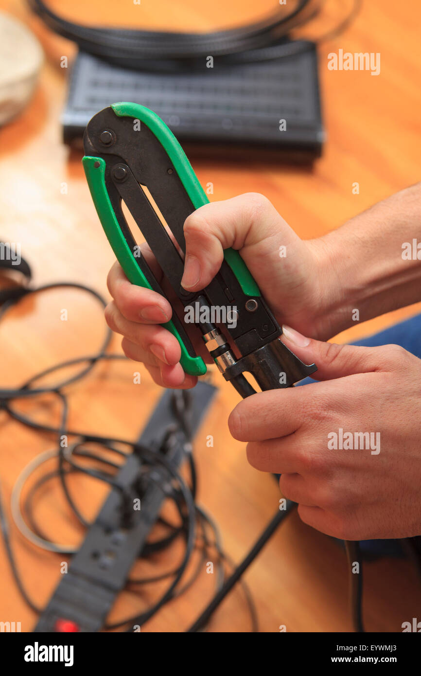 Cable installer using a crimping tool to add a new cable connector to a ...