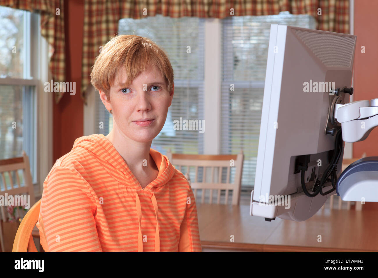 Portrait of a young woman with visual impairment sitting at her desktop ...