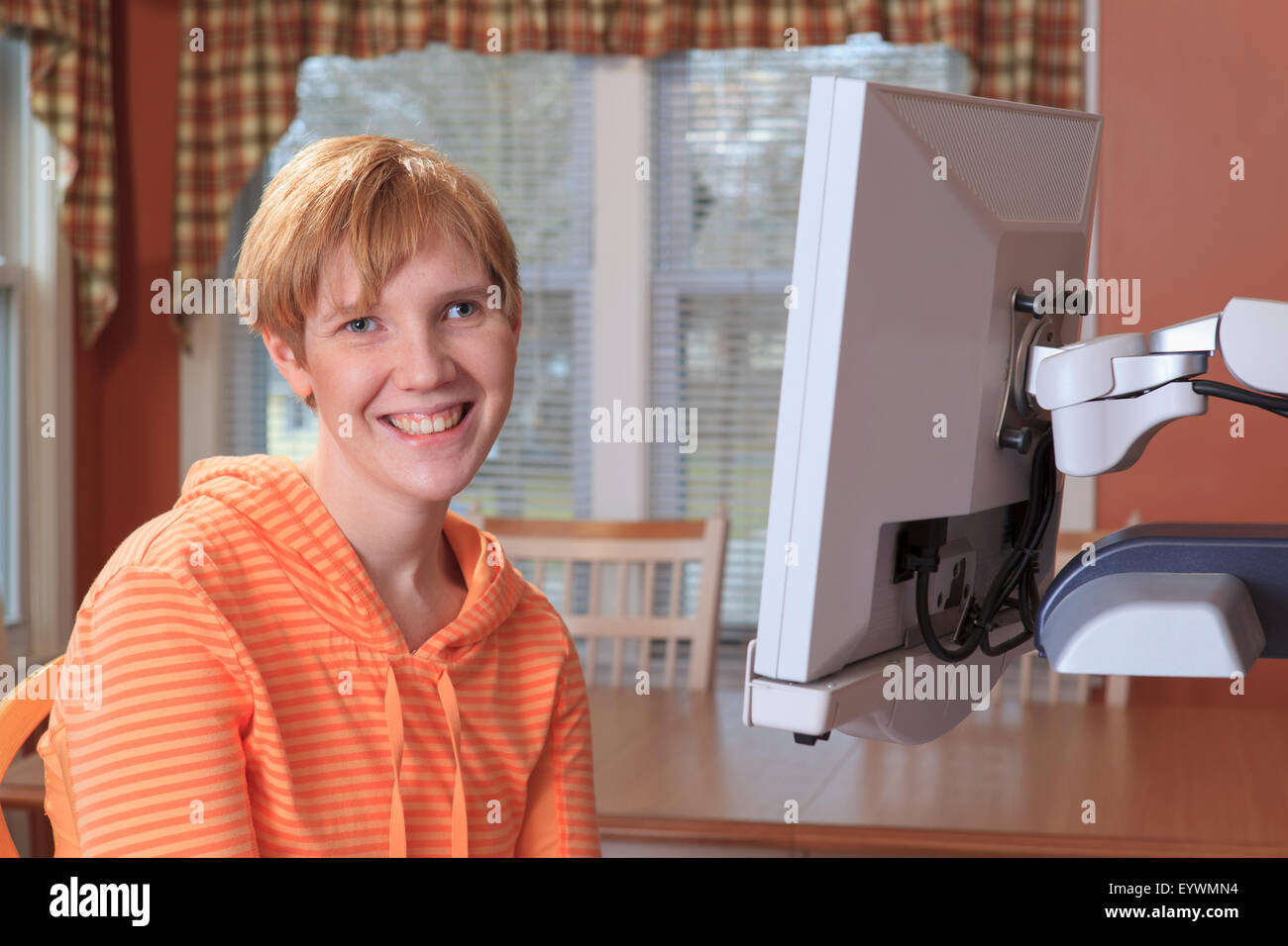 Portrait of a young woman with visual impairment sitting at her desktop ...