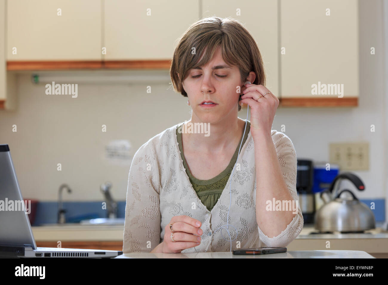 Blind woman using assistive technology ear plugs to listen to her cell ...