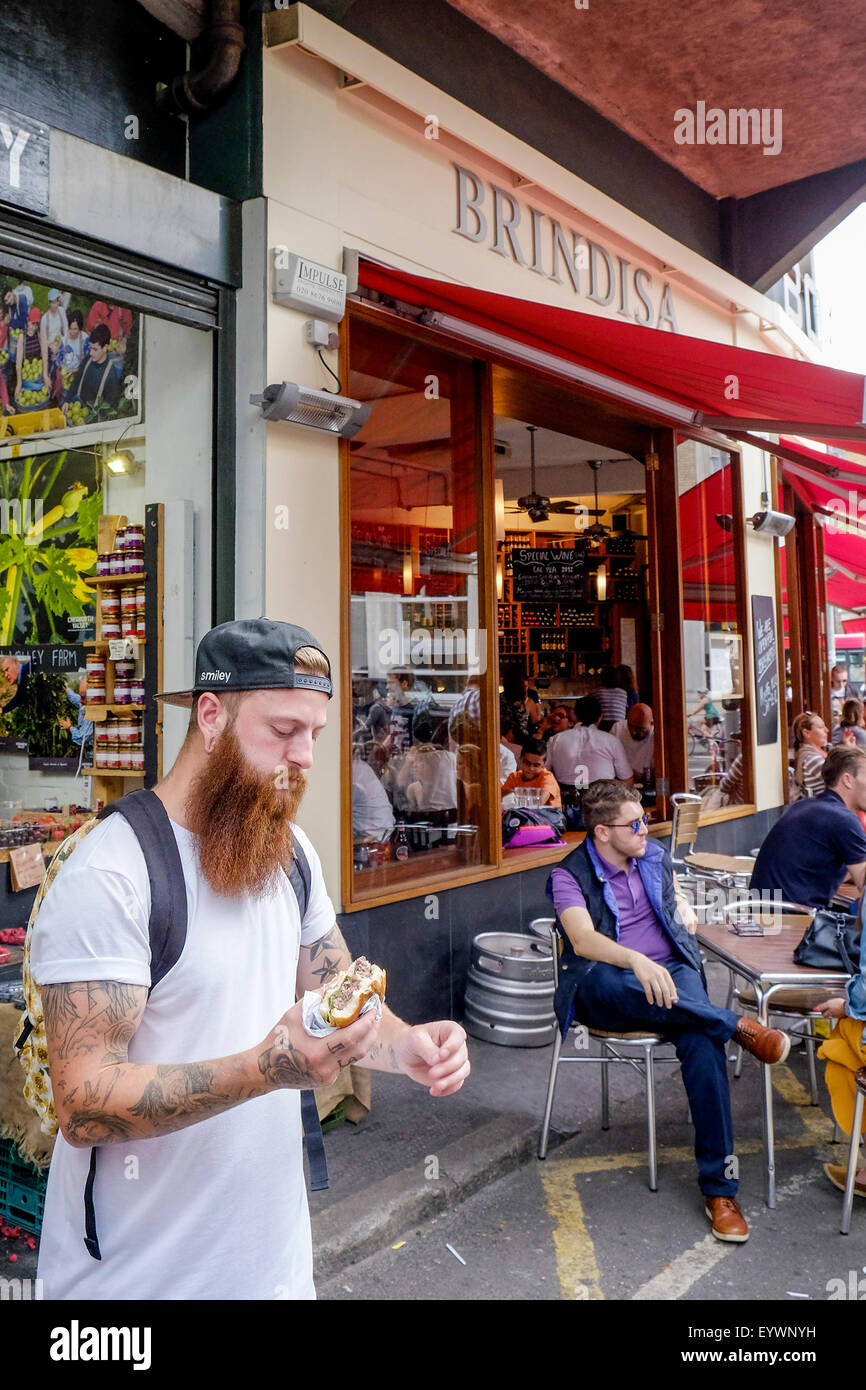 A man with a hipster bear eats a burger at Borough Market in London ...