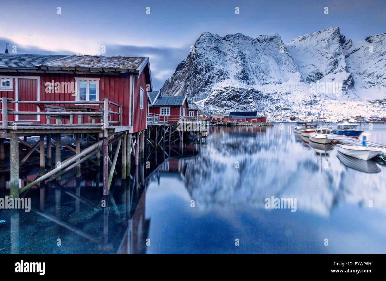 Snowy mountains and the typical red houses reflected in the cold sea at ...