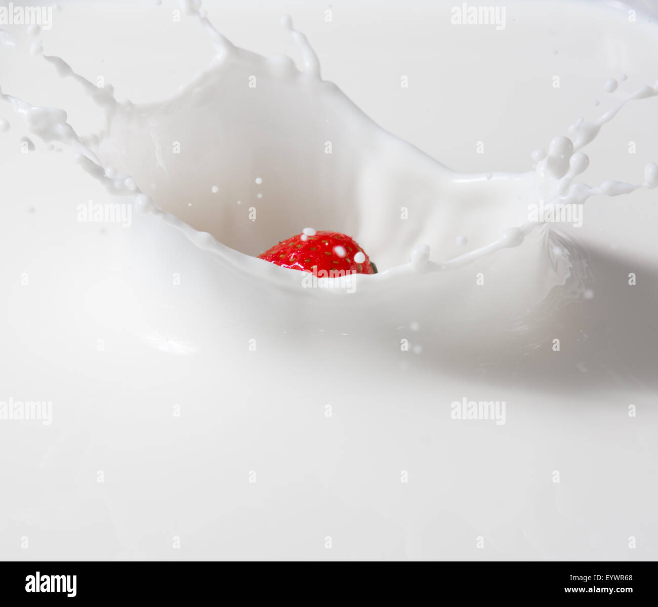 Red strawberry falling into white milk creating splash Stock Photo - Alamy