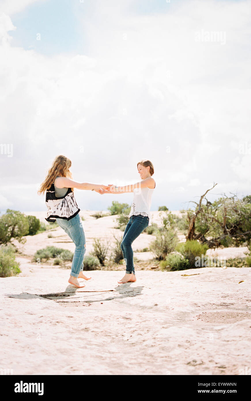 Two barefoot woman holding hands, dancing Stock Photo - Alamy