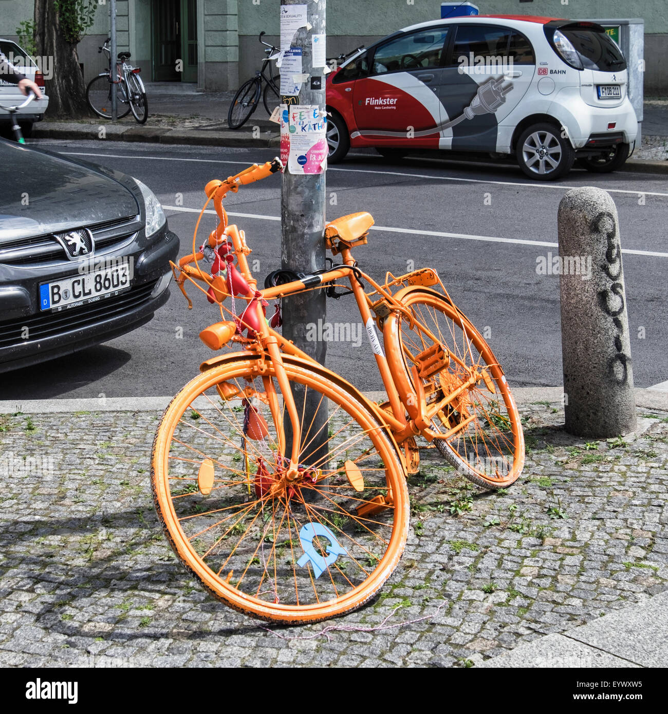 Orange bicycle and electric car in Berlin Street Stock Photo - Alamy