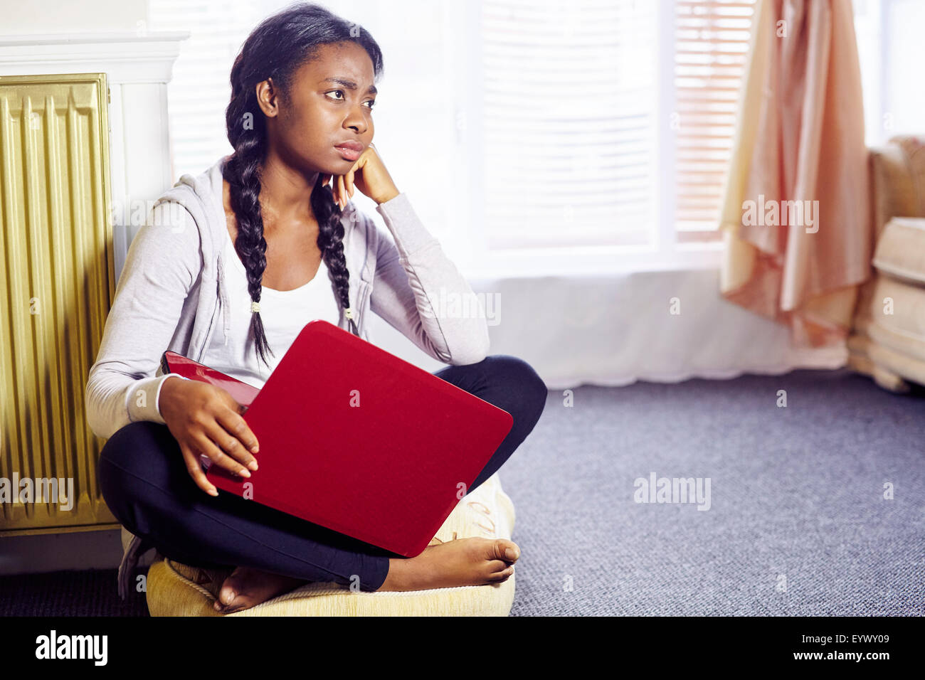 Frustrated ethnic girl sat indoors Stock Photo - Alamy