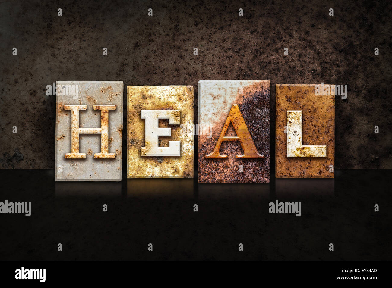 The word "HEAL" written in rusty metal letterpress type on a dark ...