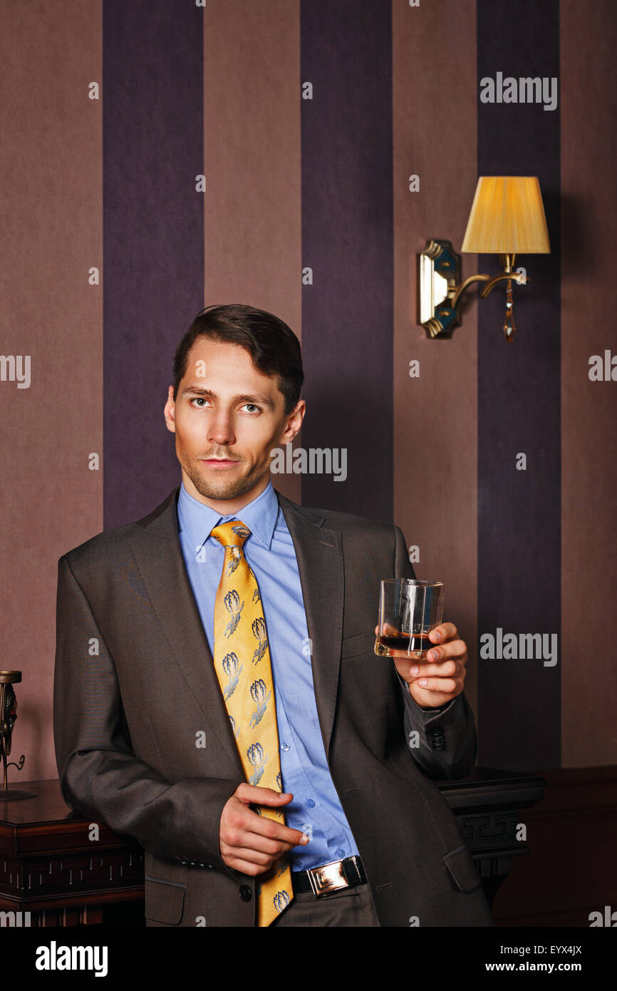 Successful businessman holding a glass of whiskey. Man celebrates good ...