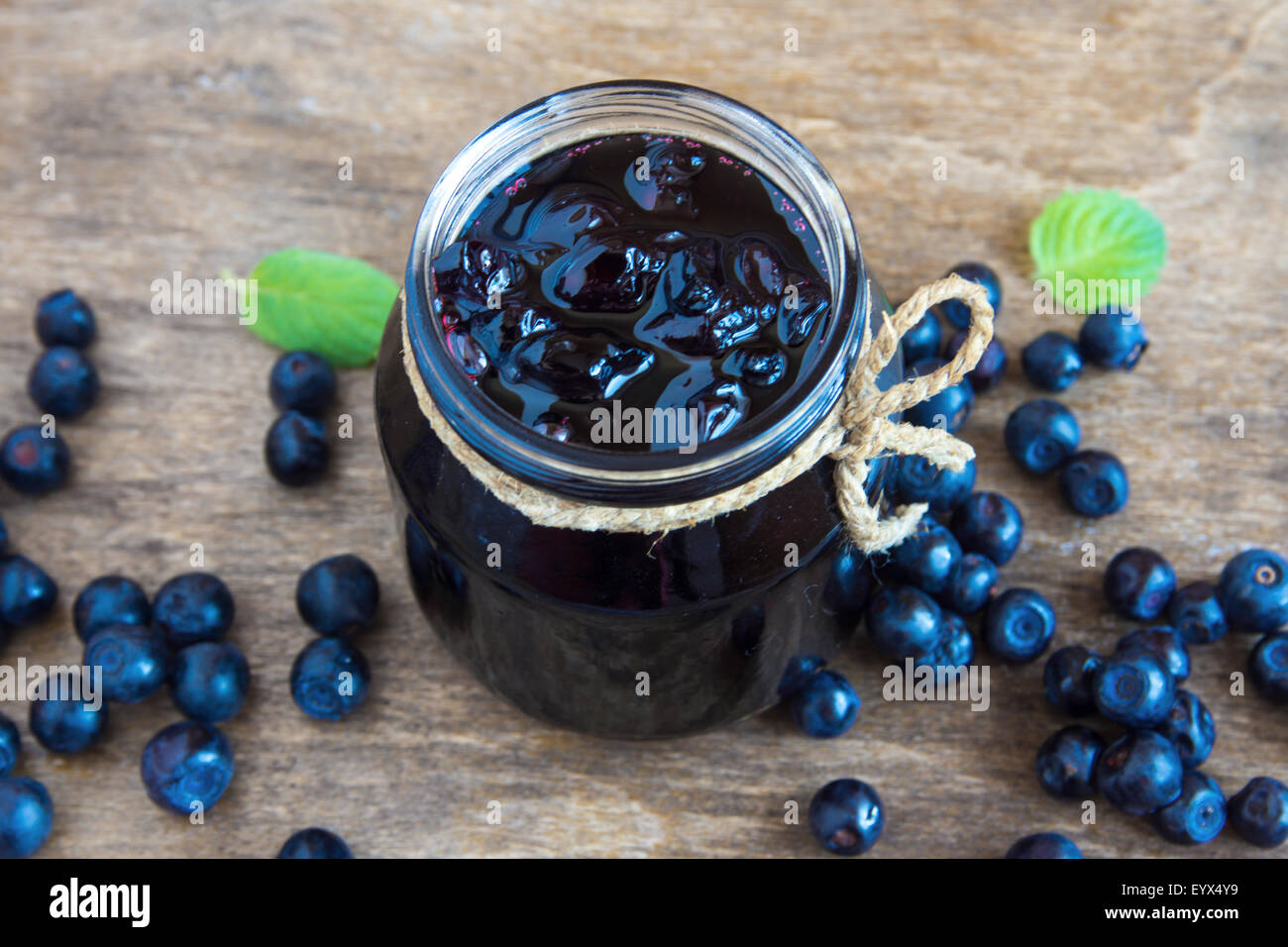 Blueberry jam in jar with berries and leaves over rustic wooden table ...