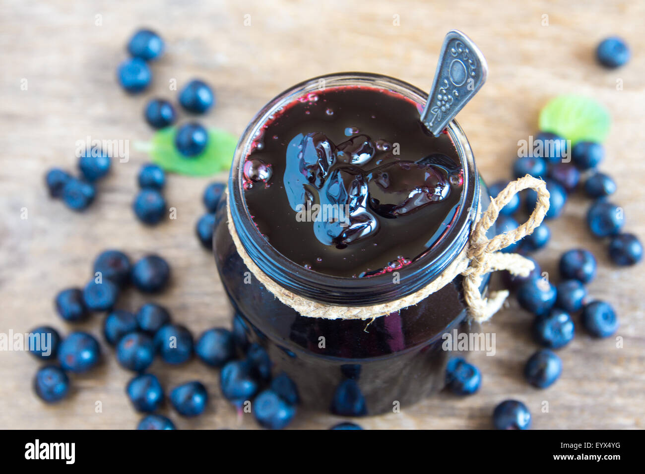 Blueberry jam in jar with berries and leaves over rustic wooden table ...