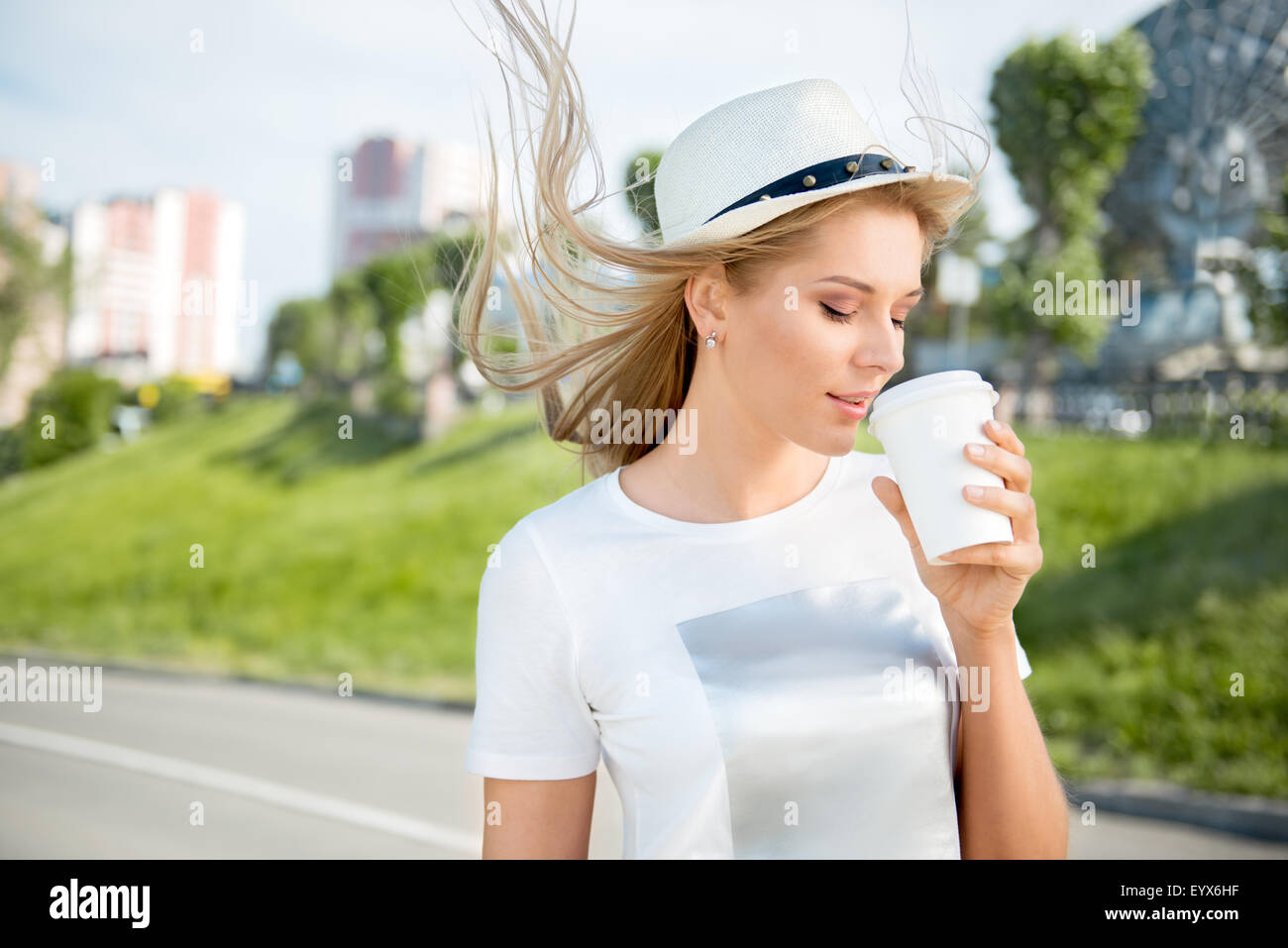 Beautiful young woman with a takeaway coffee cup, walking along the ...