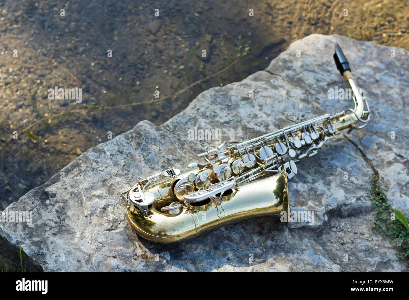 Summer Jazz saxophone in nature lying on rocks lakeside Stock Photo - Alamy