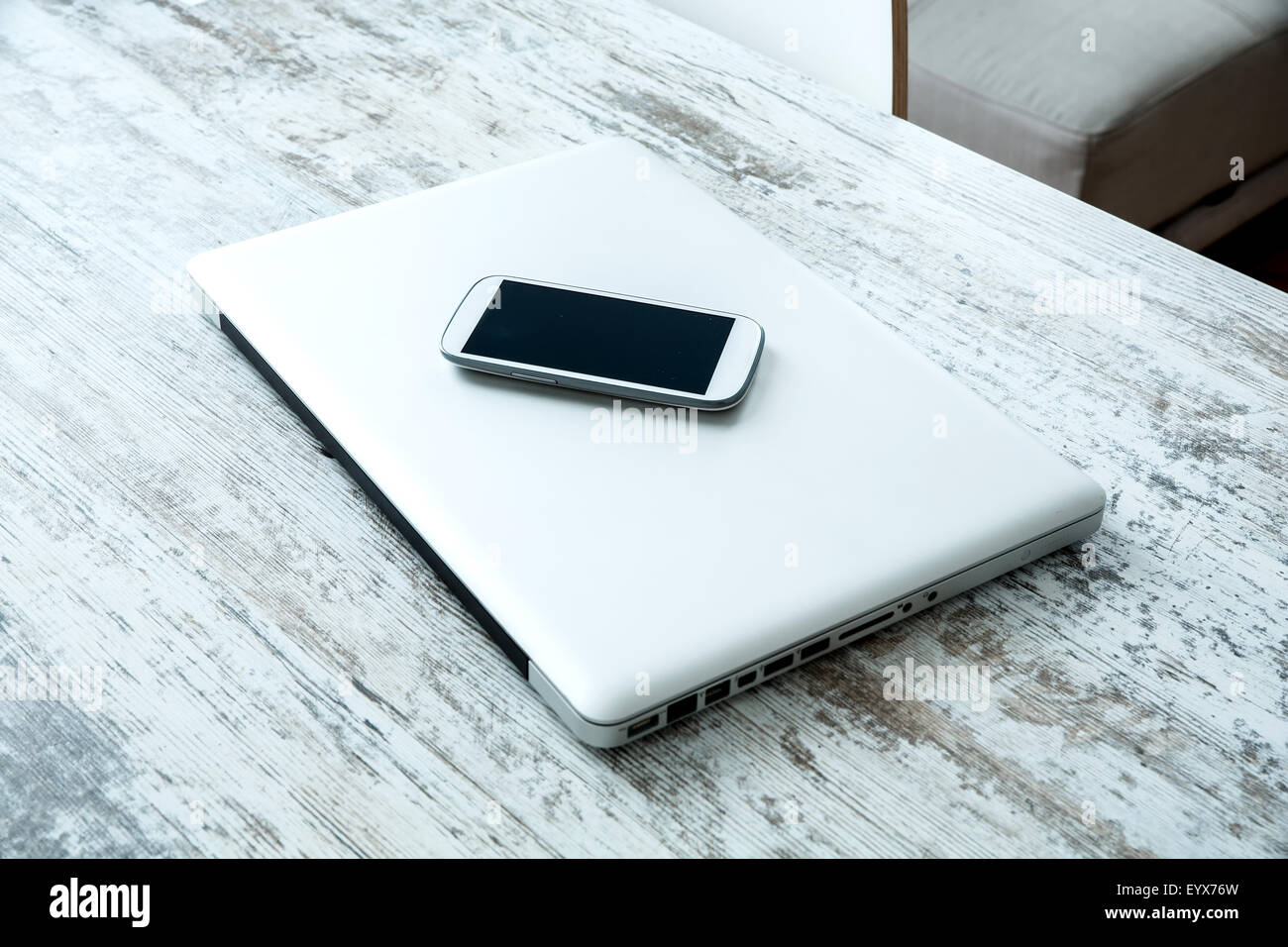 A Smartphone and a switched off laptop computer on a wooden Desktop ...