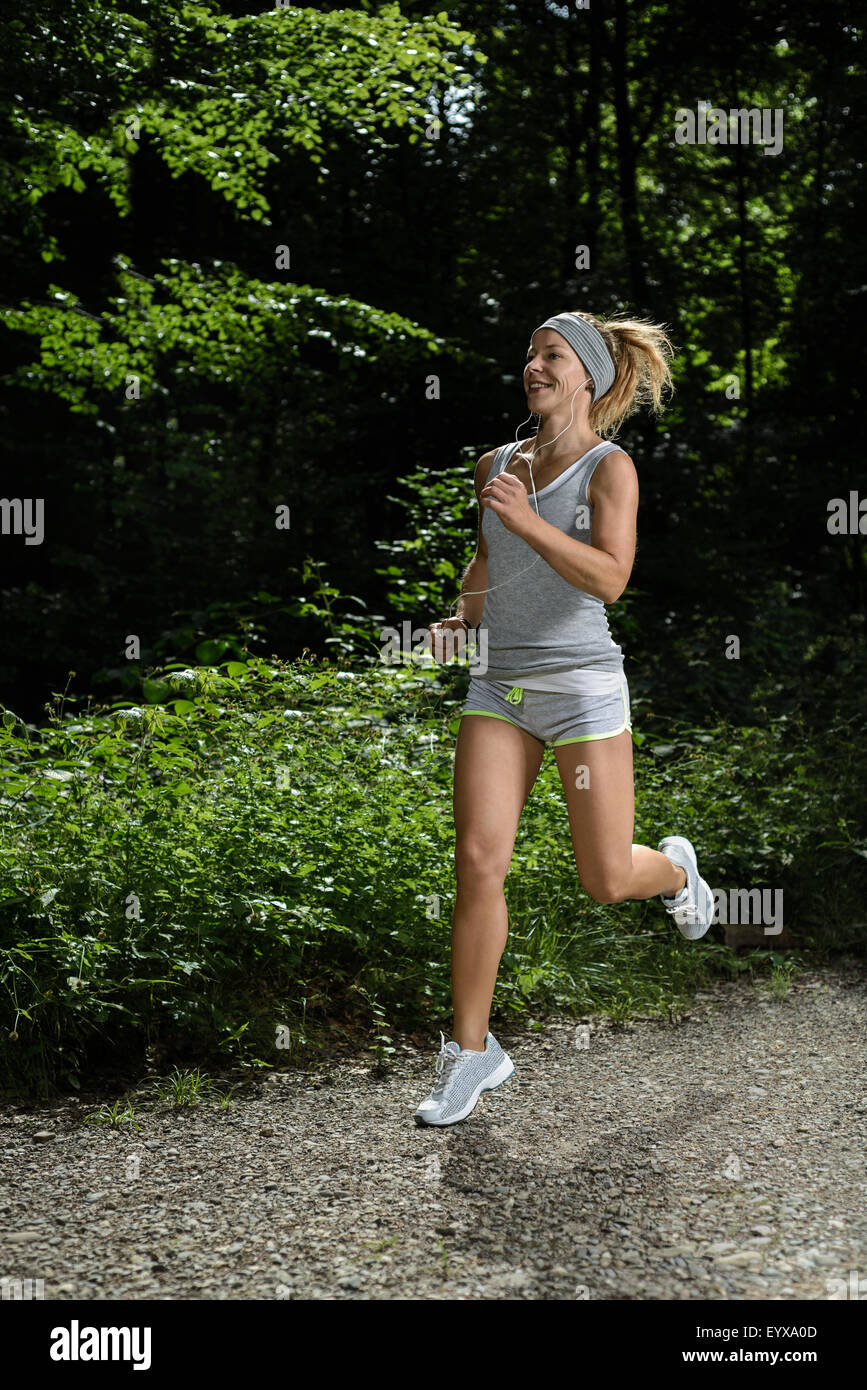 Fit woman jogger enjoying jogging on forest path Stock Photo - Alamy