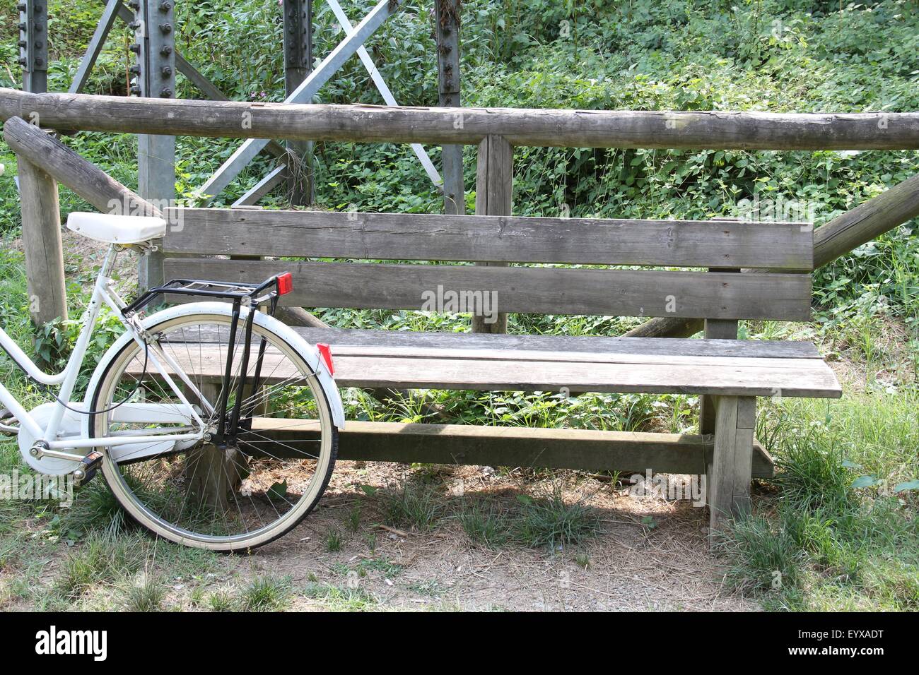 A woman's bicycle, leaning against a park bench, wooden structure, near ...