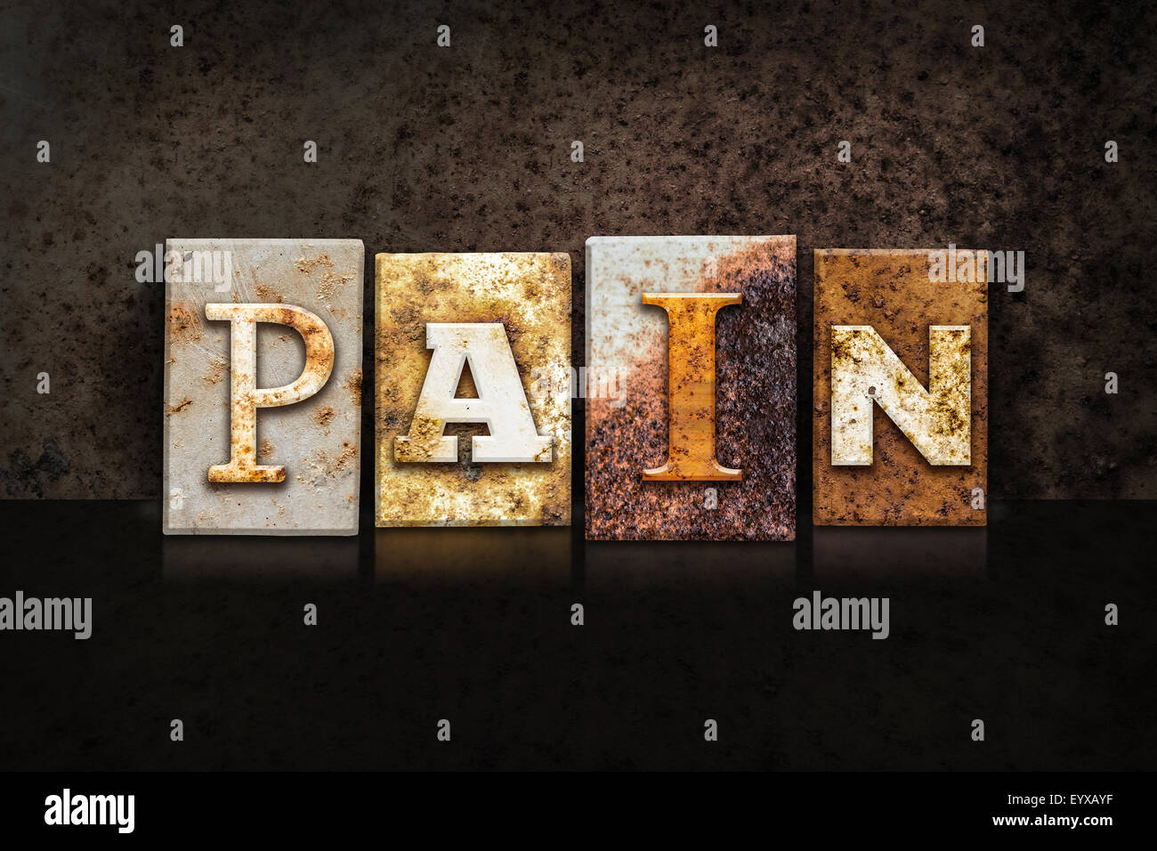 The word "PAIN" written in rusty metal letterpress type on a dark ...