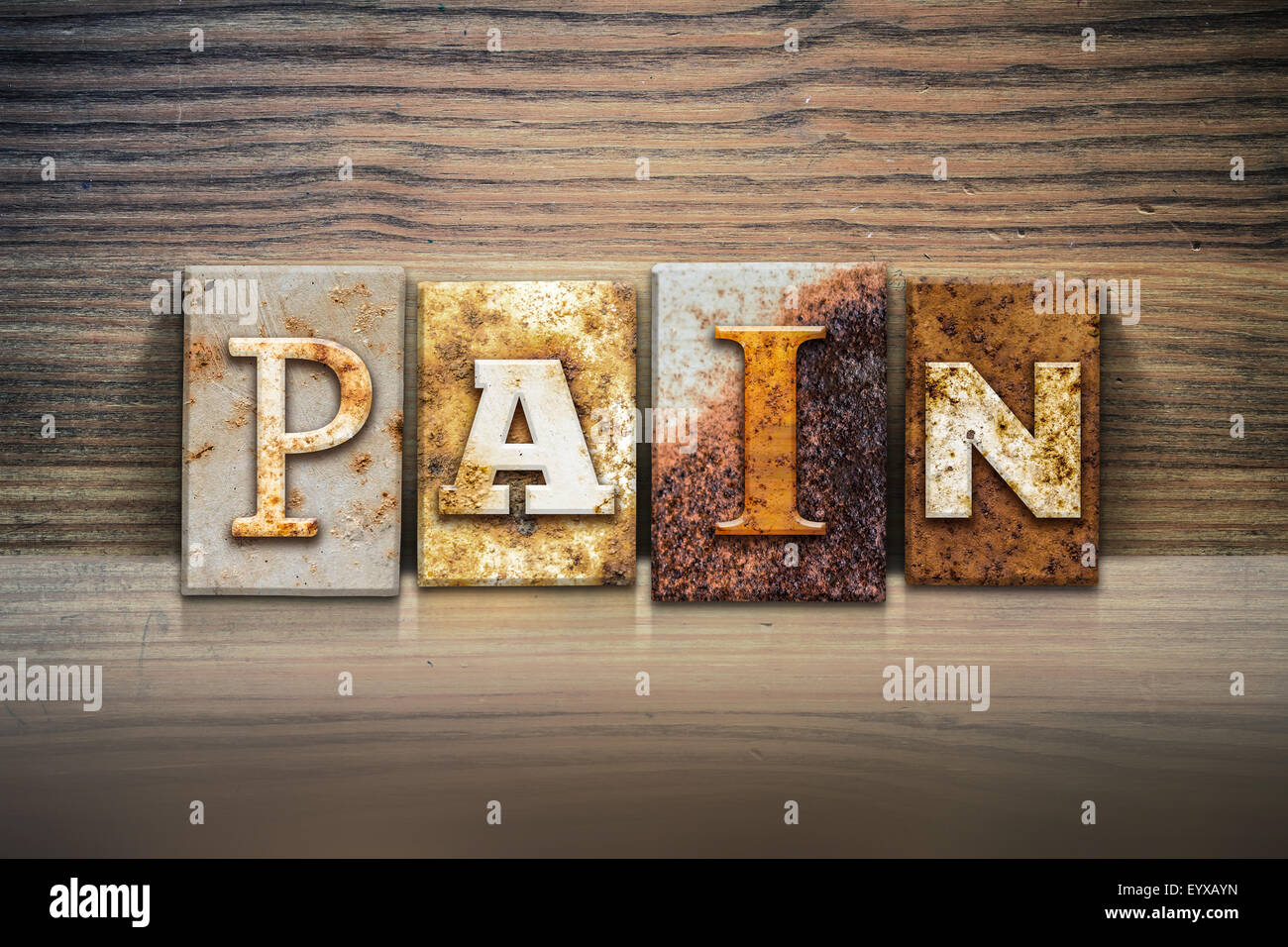 The word "PAIN" written in rusty metal letterpress type sitting on a ...