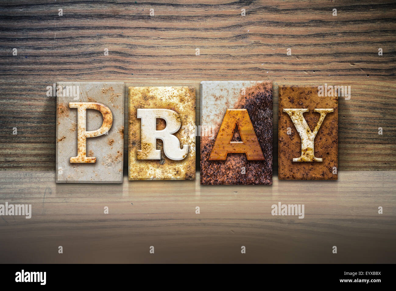 The word "PRAY" written in rusty metal letterpress type sitting on a ...
