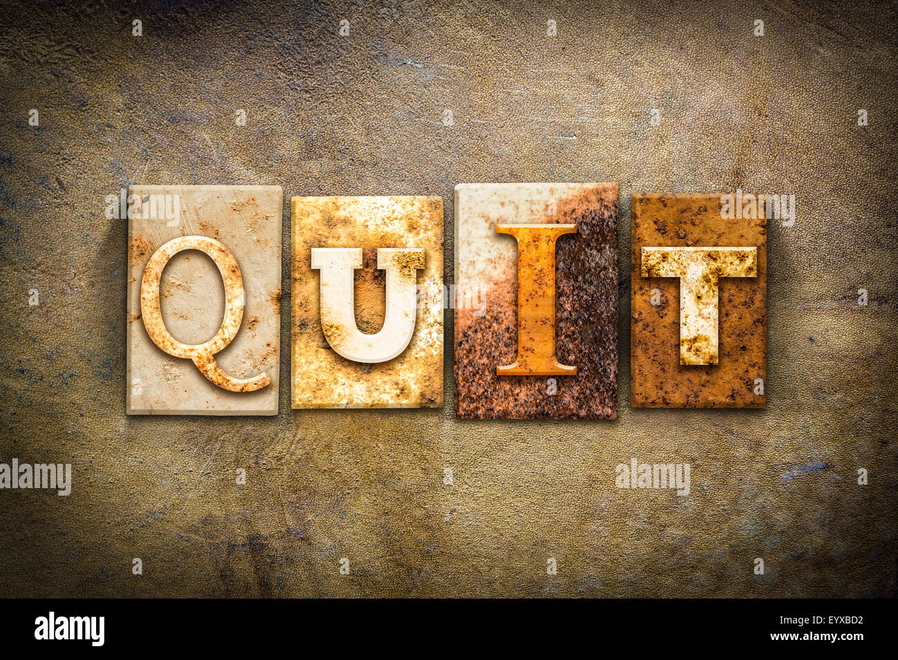 The word "QUIT" written in rusty metal letterpress type on an old aged ...