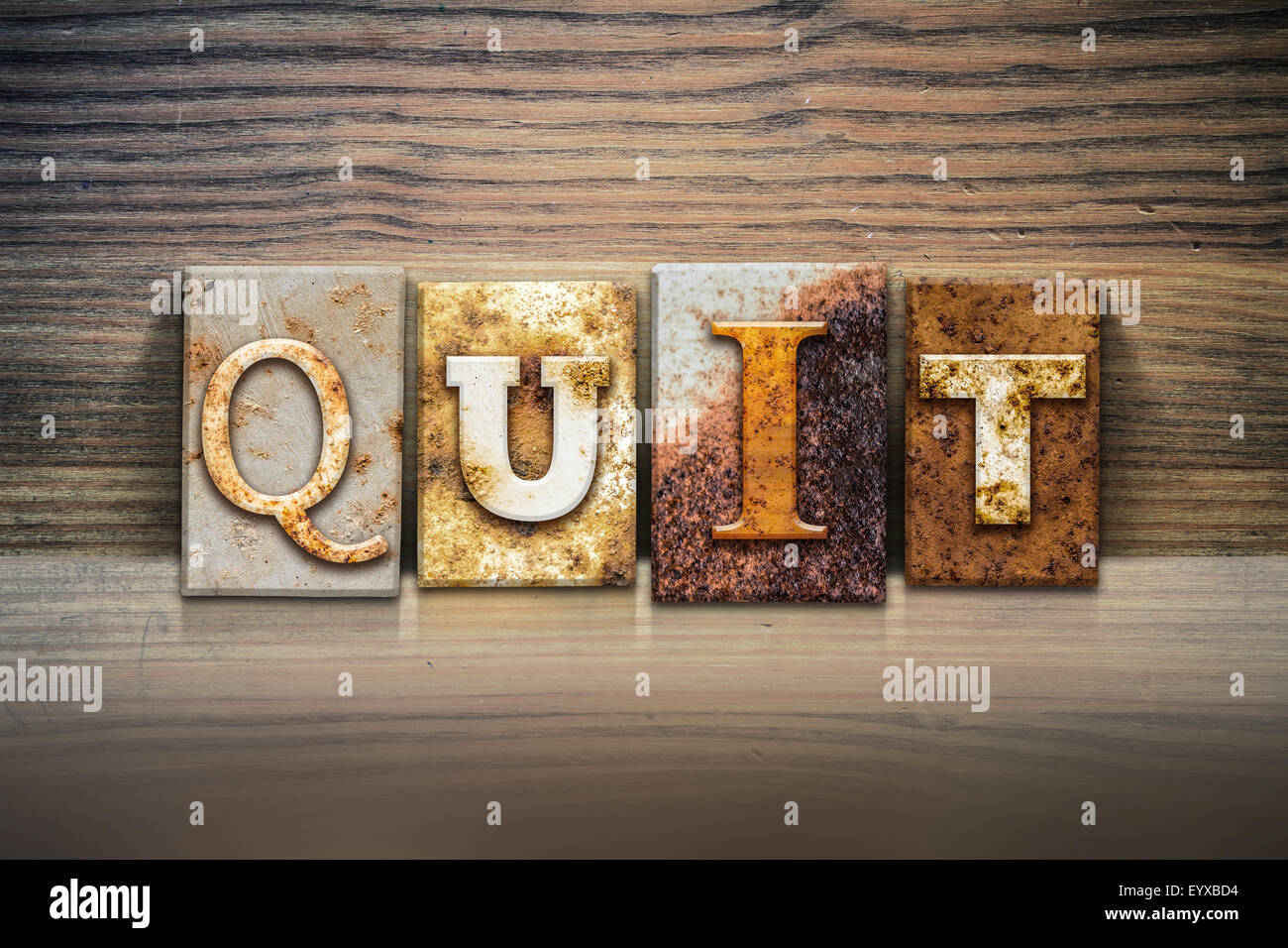 The word "QUIT" written in rusty metal letterpress type sitting on a ...