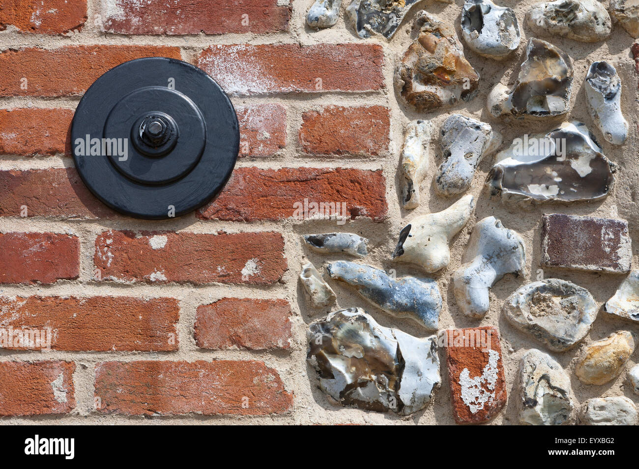Detail of a flint and red brick wall, with circular patress wall tie ...