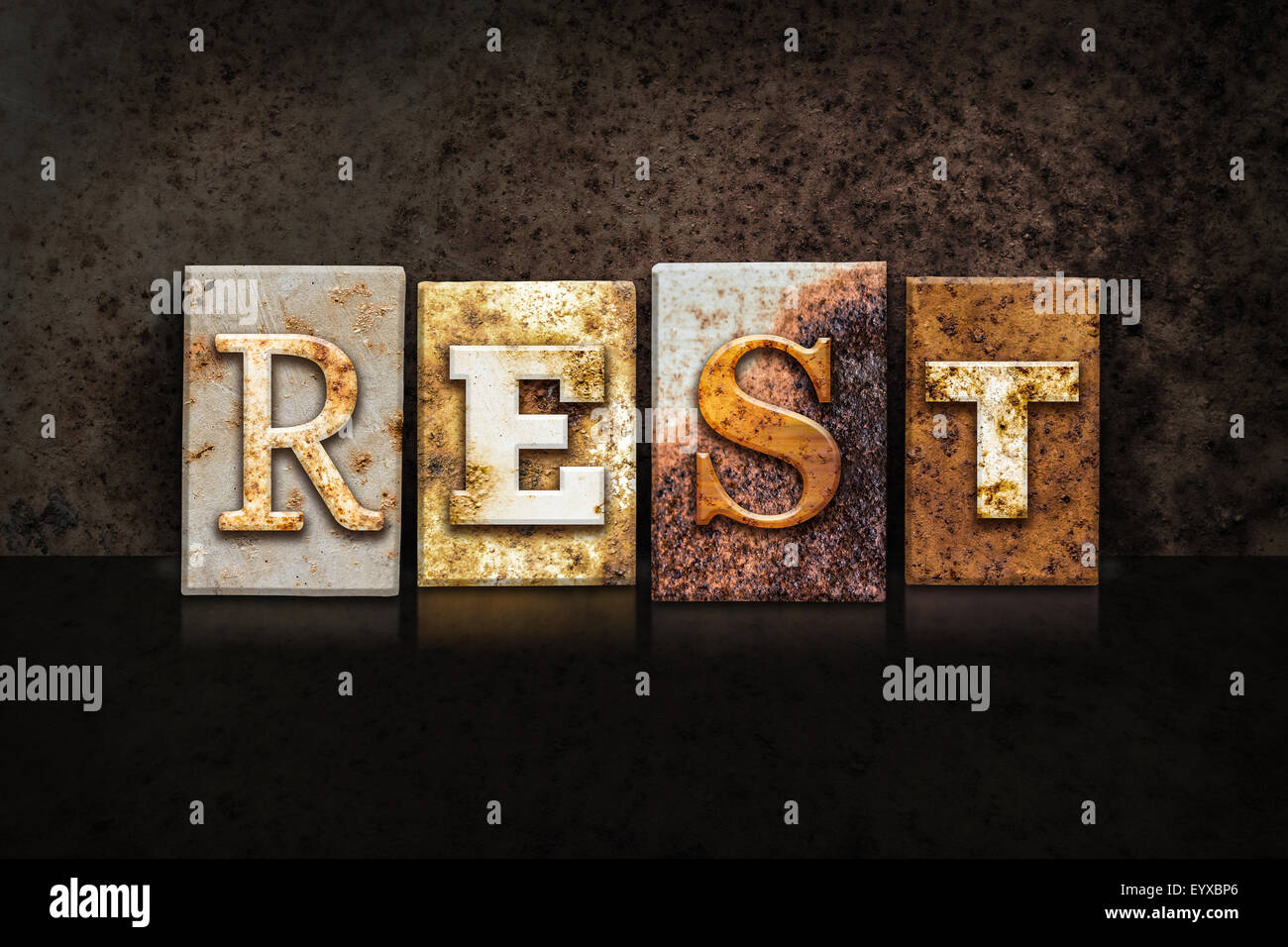 The word "REST" written in rusty metal letterpress type on a dark ...