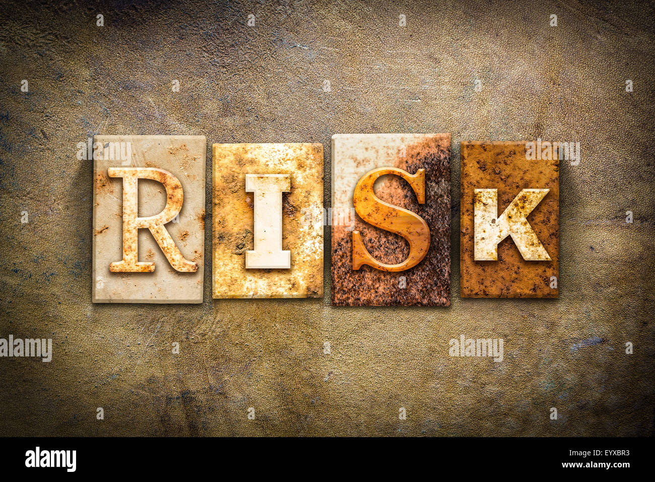 The word "RISK" written in rusty metal letterpress type on an old aged ...
