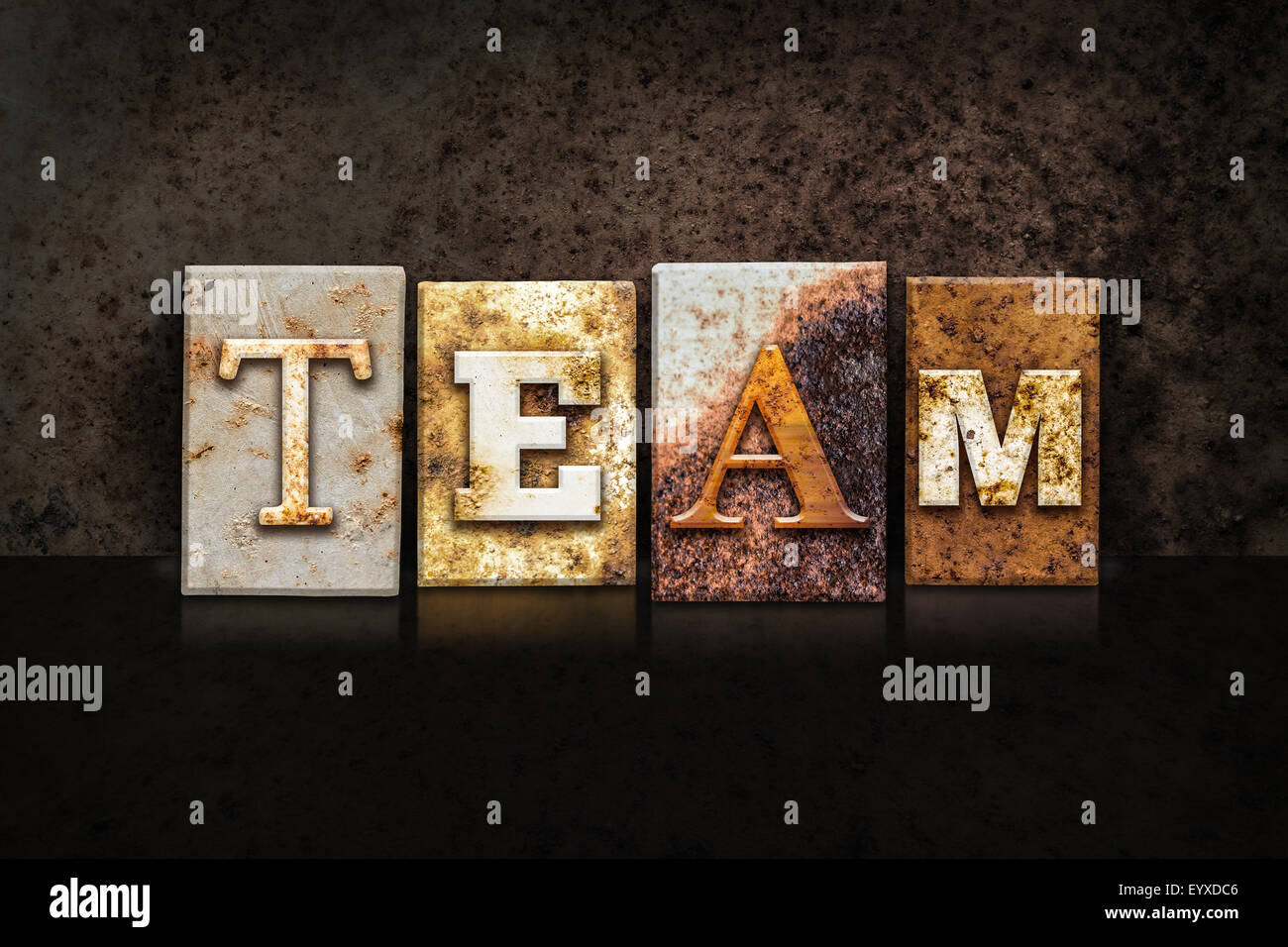 The word "TEAM" written in rusty metal letterpress type on a dark ...