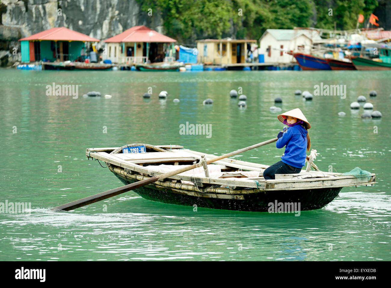 Woman rowing wooden rowboat and floating houses, Vung Vieng fishing ...