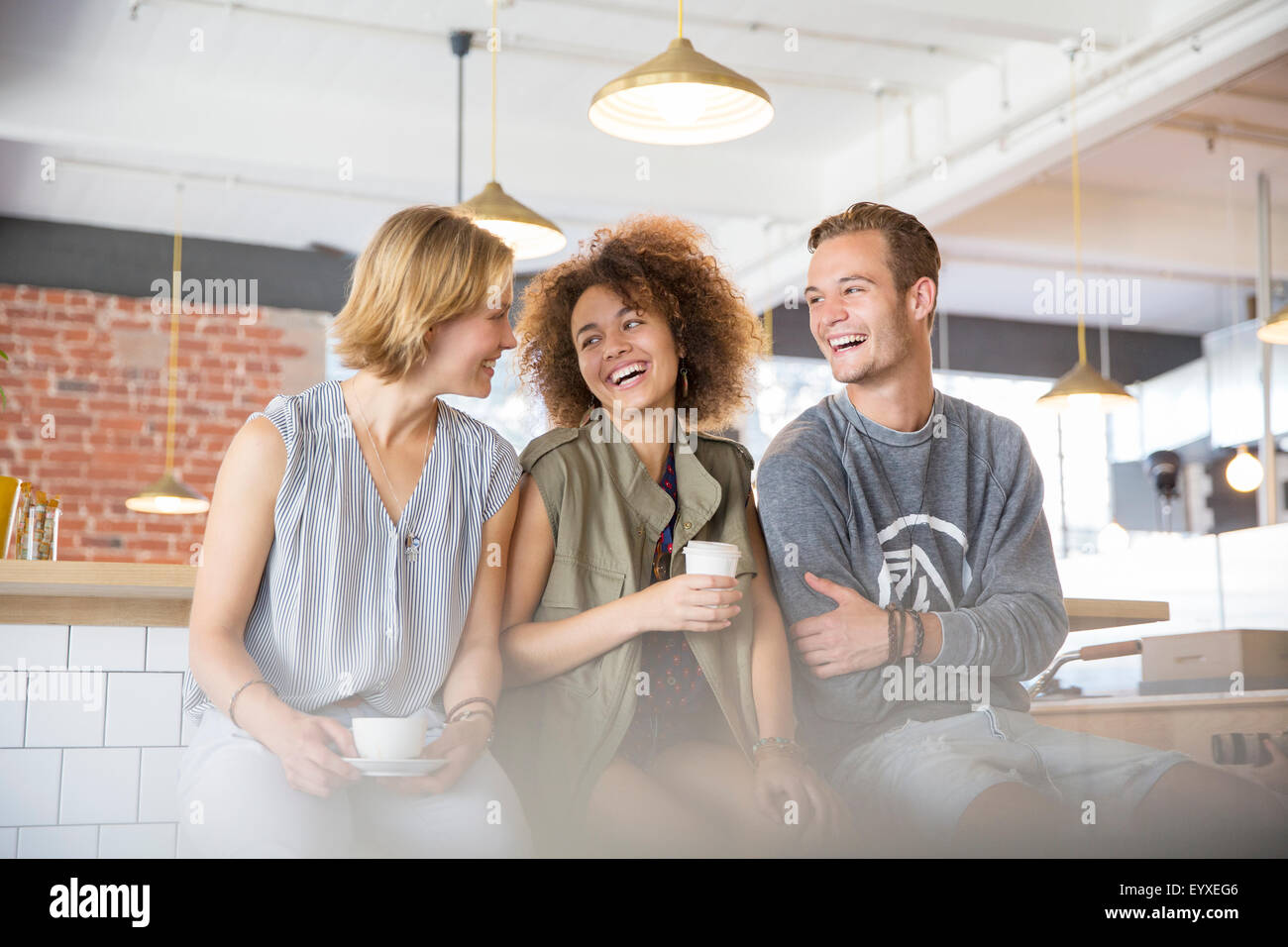 Laughing friends drinking coffee in cafe Stock Photo - Alamy