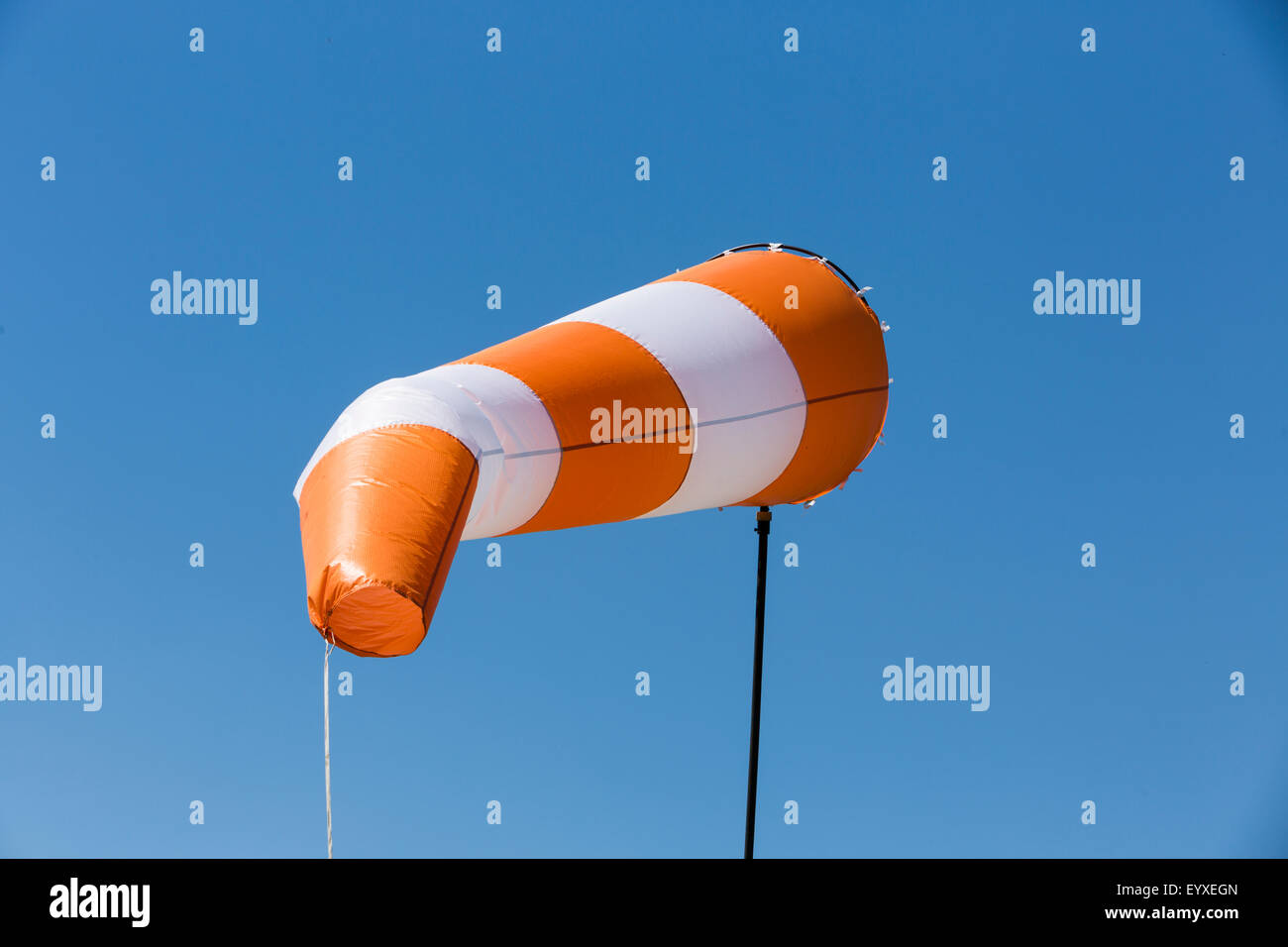 Red and white windsock wind filled blue sky background Stock Photo - Alamy