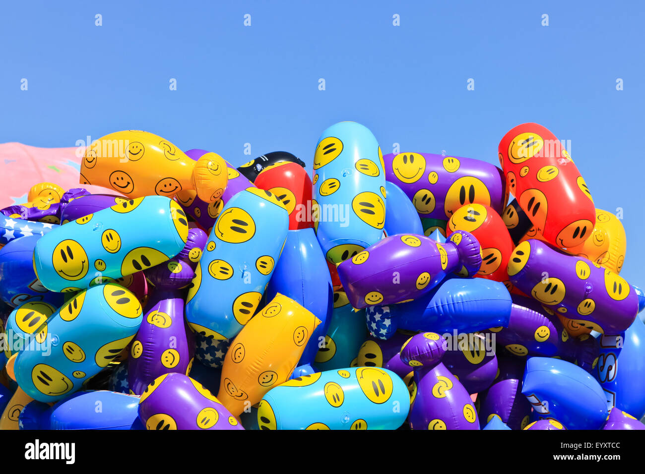 Blowup toys in bright colors with yellow smiley faces on them at the ...