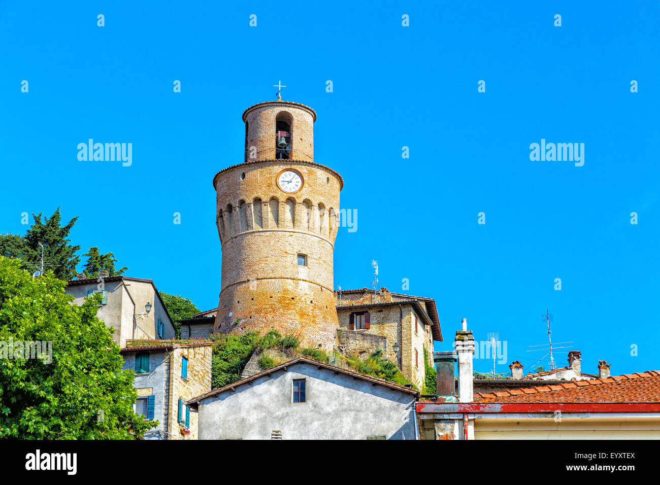 Clock tower with brick walls overlooking a countryside village in Italy ...