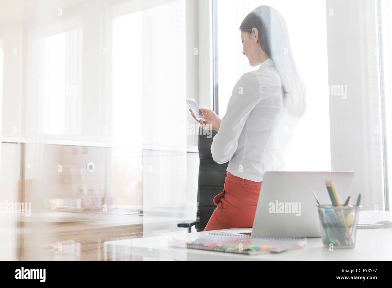 Businesswoman texting with cell phone in office Stock Photo - Alamy