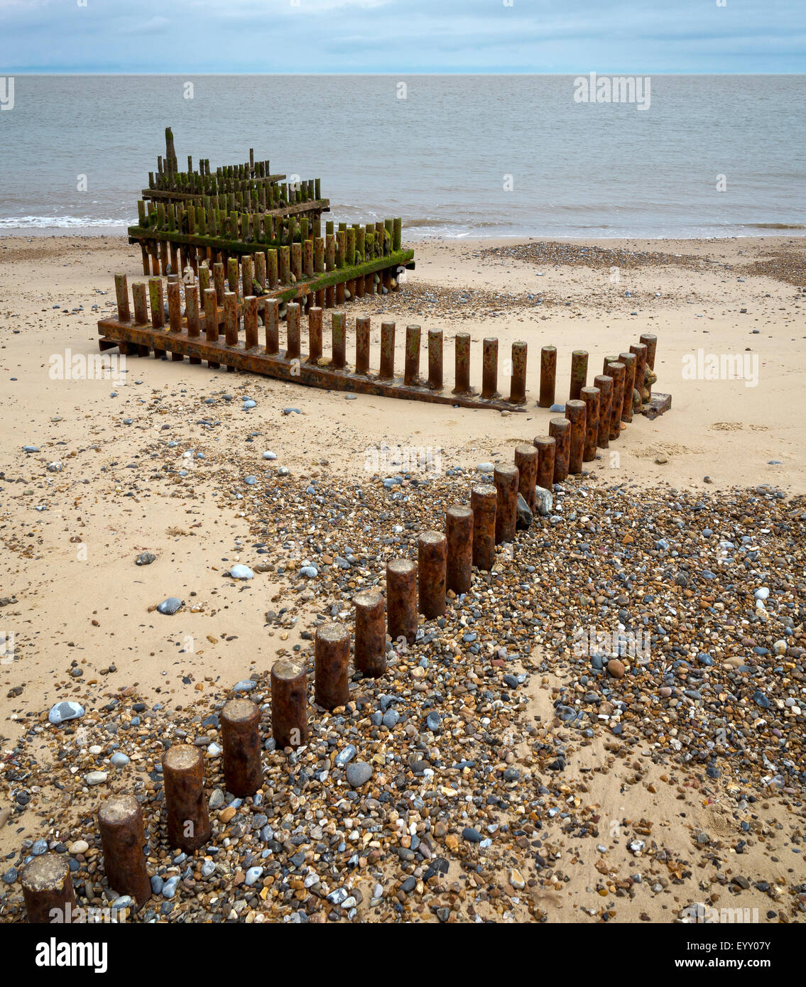 Metal groynes covered in sea weed zigzagging out to sea on a Norfolk ...