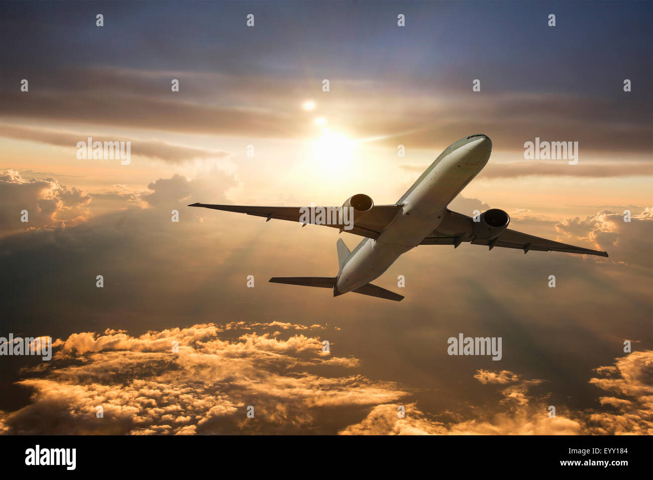 Airplane flying in dramatic sunset sky Stock Photo - Alamy