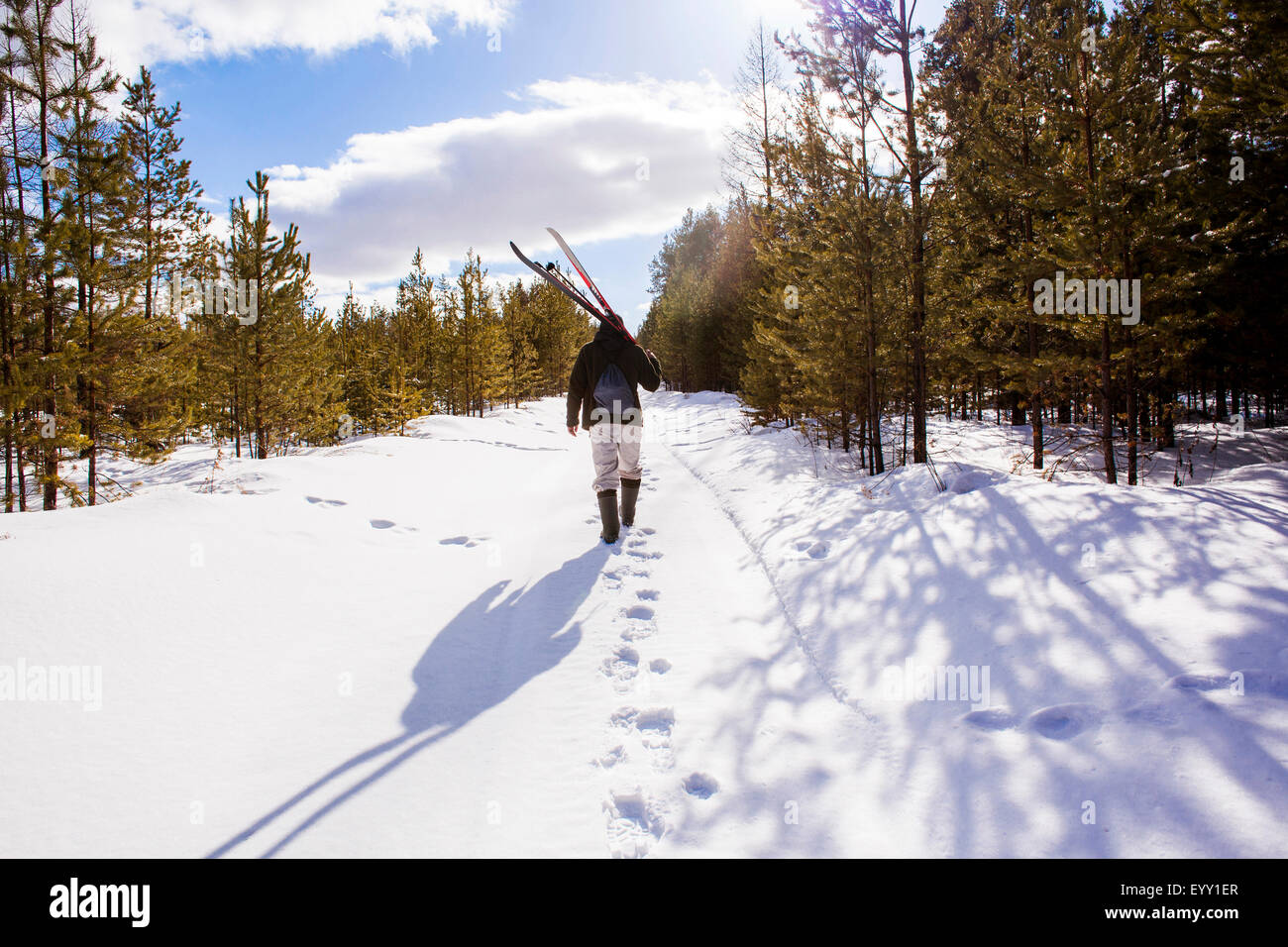 Mari man carrying skis on snowy path Stock Photo - Alamy