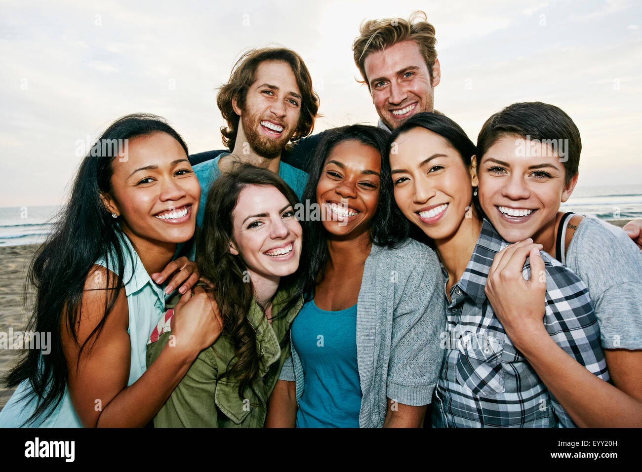 Smiling friends standing on beach Stock Photo - Alamy