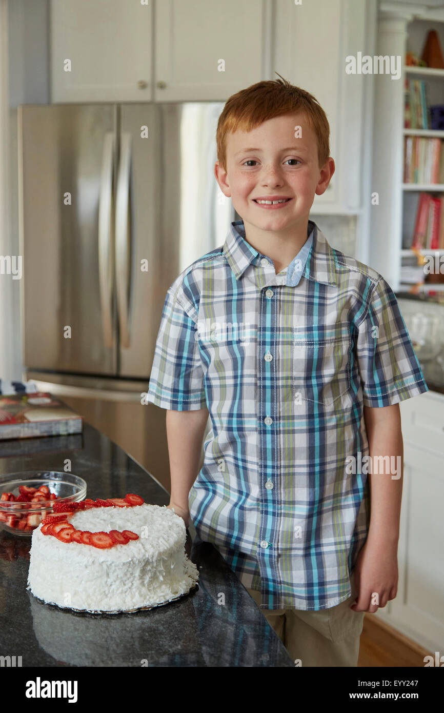 Caucasian boy standing with cake in kitchen Stock Photo - Alamy