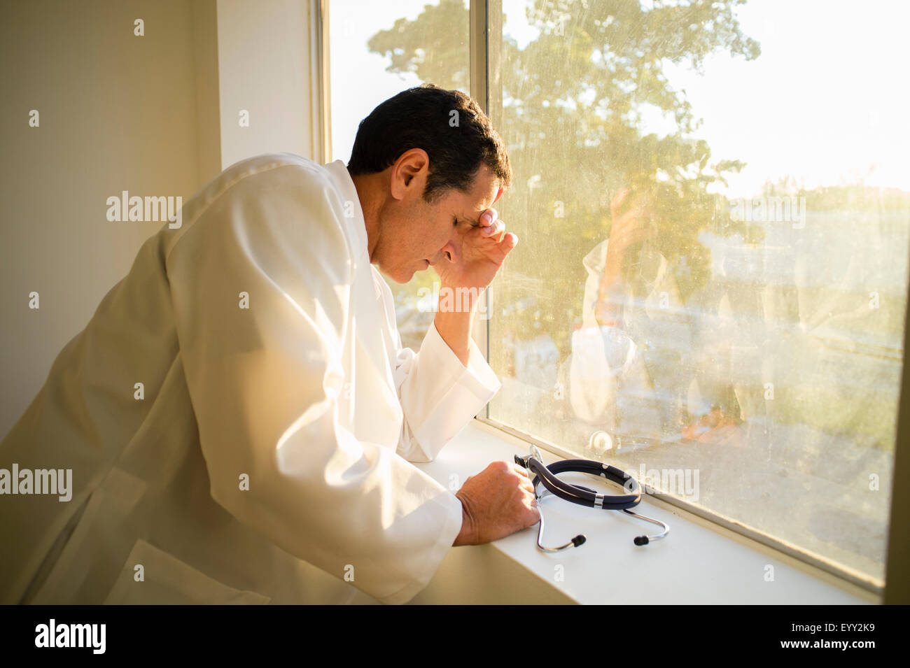 Stressed Hispanic doctor standing at window Stock Photo - Alamy
