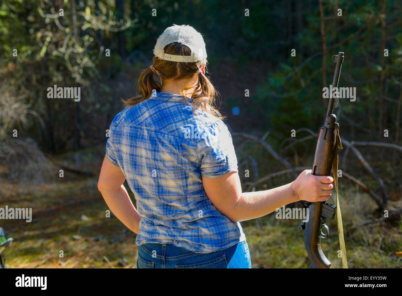 Caucasian woman carrying rifle in forest Stock Photo - Alamy