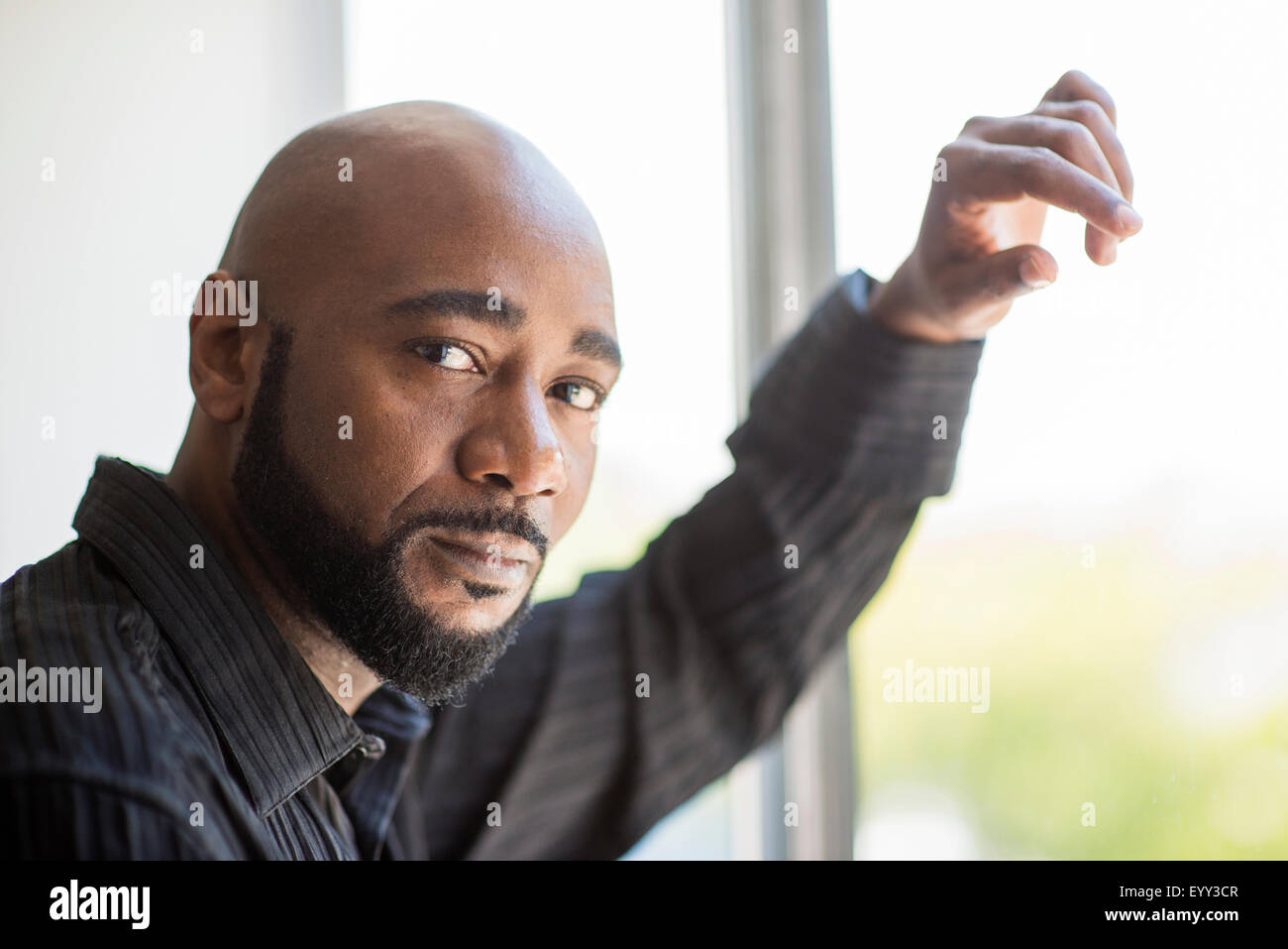 Black man standing at window Stock Photo - Alamy