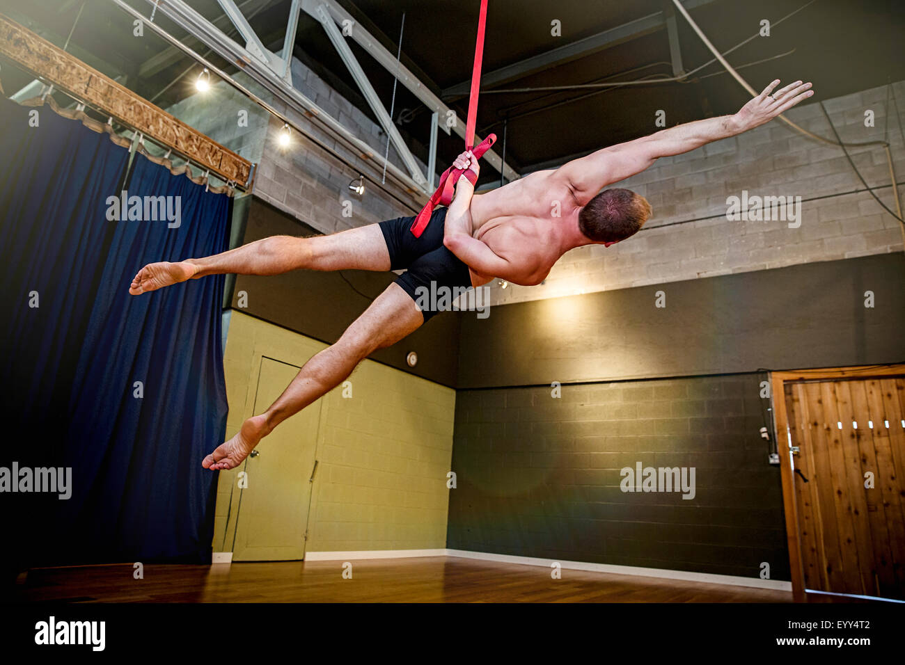 Caucasian acrobat hanging from ropes in studio Stock Photo - Alamy