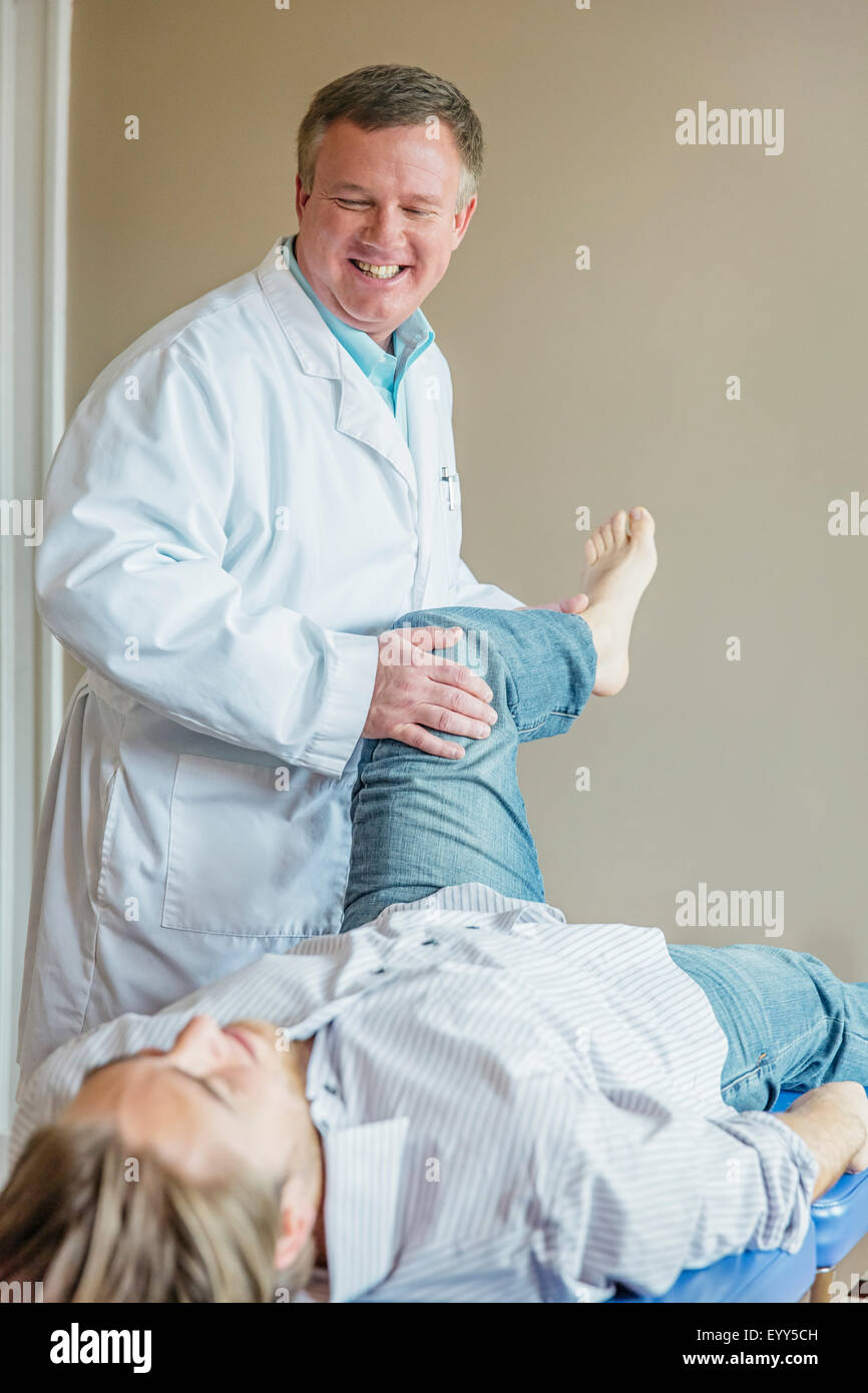 Caucasian doctor adjusting leg of patient Stock Photo - Alamy