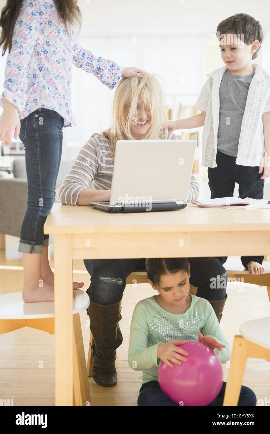 Caucasian mother using laptop with chaotic children Stock Photo - Alamy