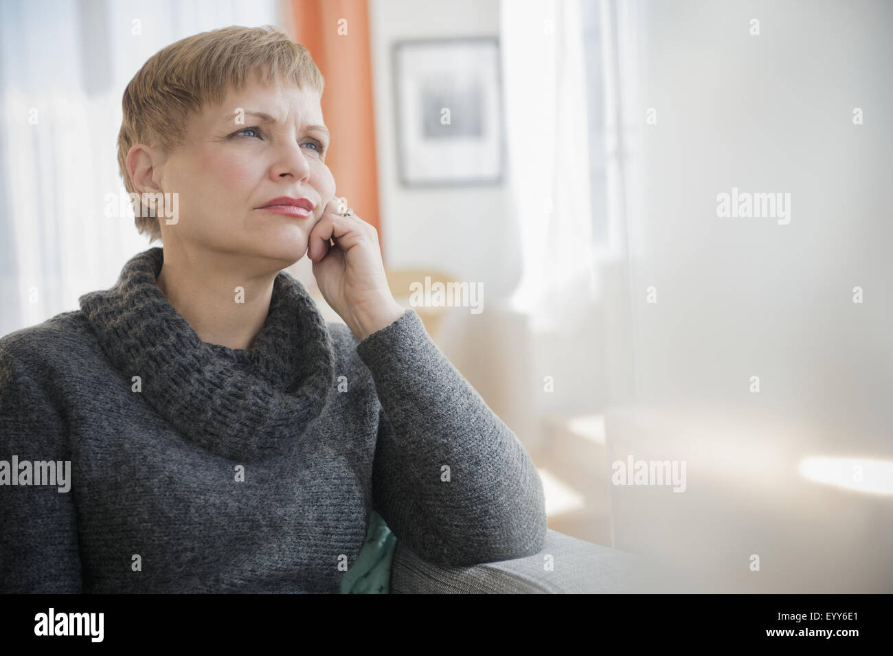 Thinking woman sitting on a sofa Stock Photo - Alamy